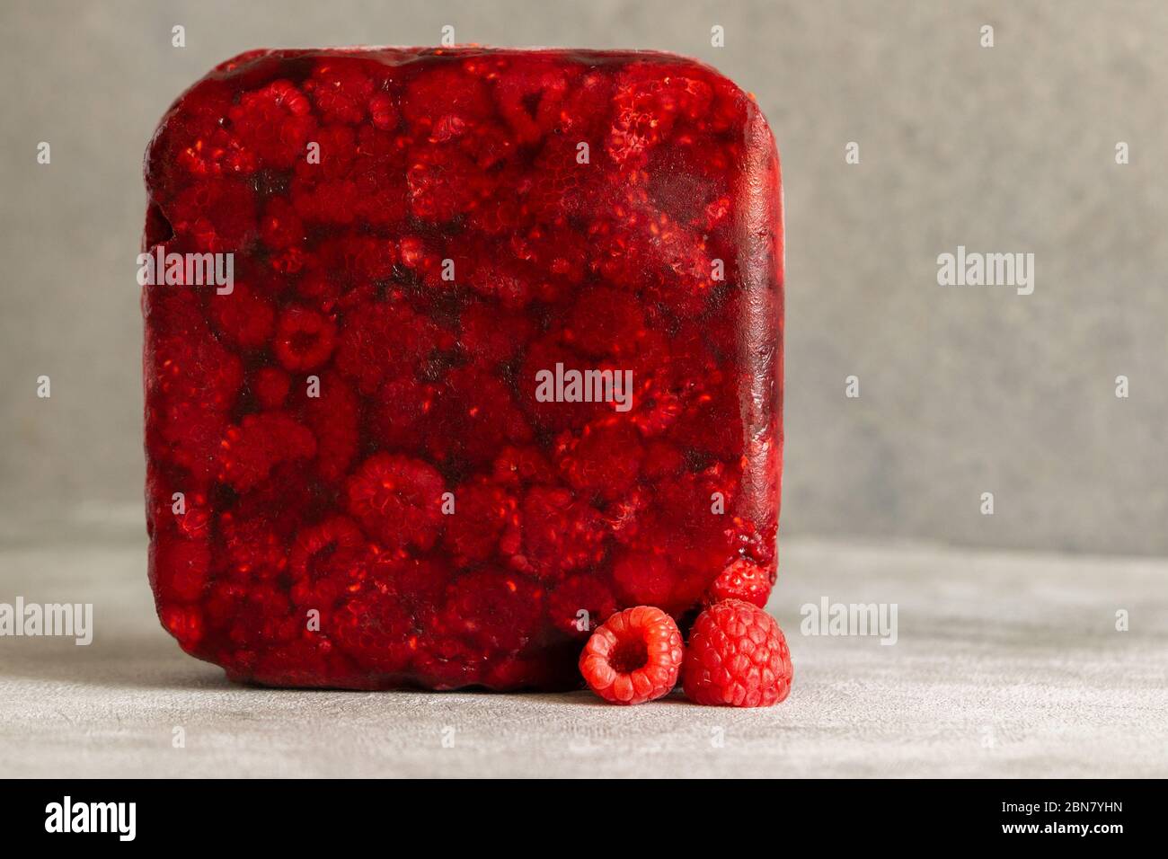 Red frozen raspberry cube near fresh raspberry. Creative photo. Copy ...