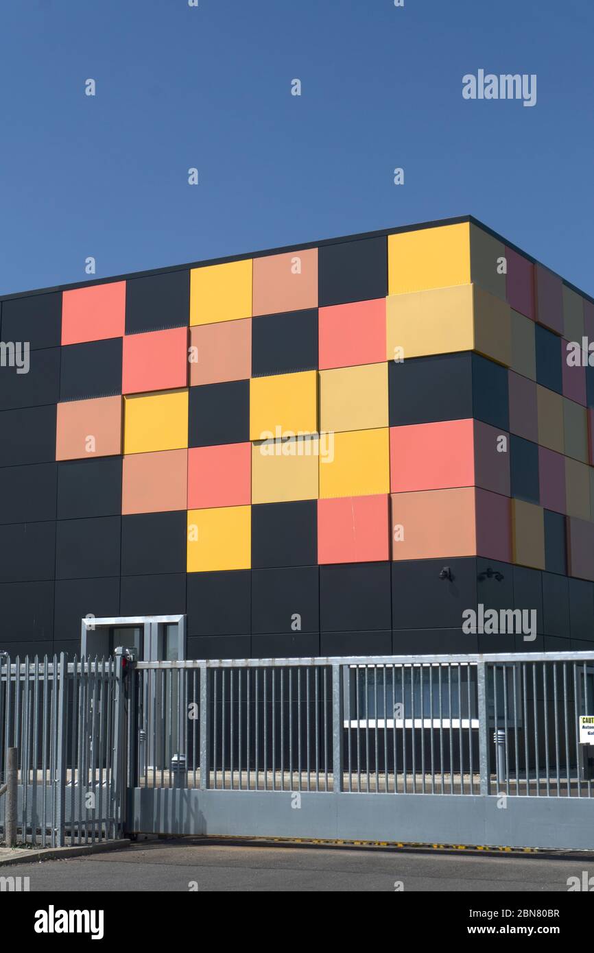 Matt black cubic building with yellow and red tiles in one corner as ...