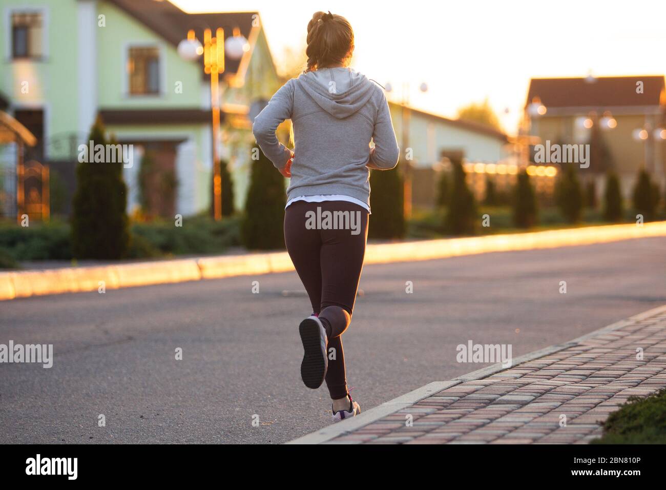 Young female runner, athlete is jogging in the city street in spring ...