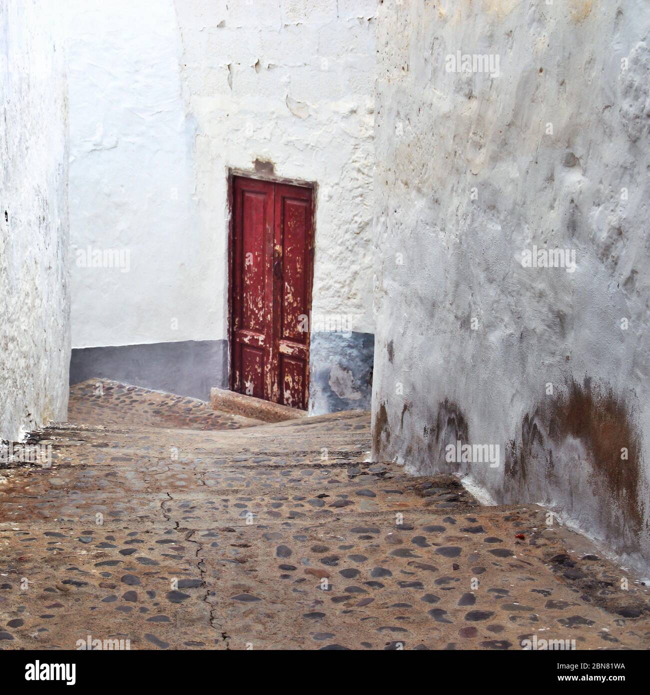 Narrow hallway with old concrete stairs and a red wooden rusty door ...