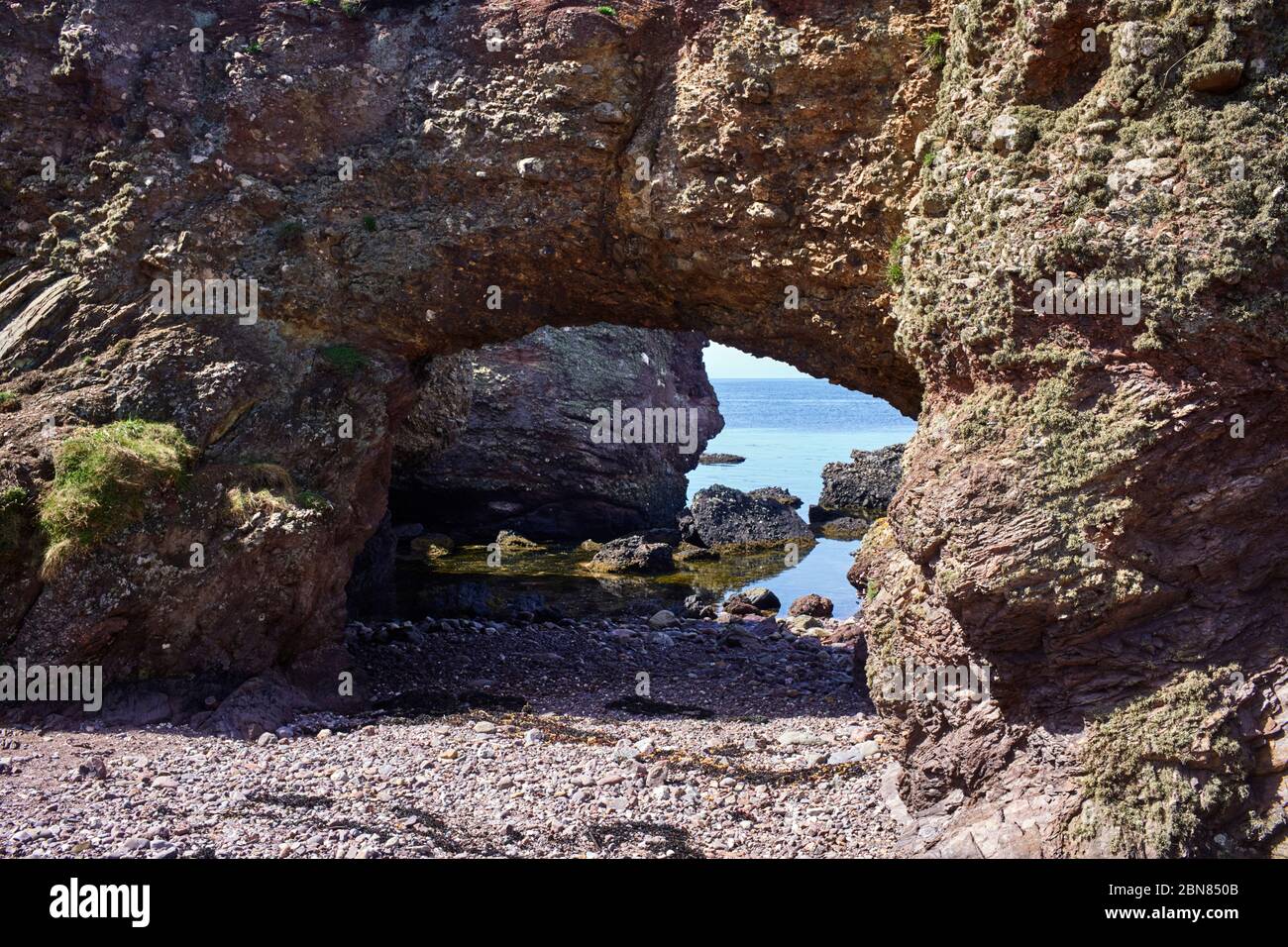 Langness peninsular with arch in rocks and beach in foreground ...