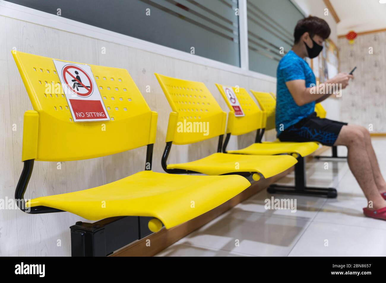 Yong male sitting on the public chair has restricted no-sitting sign to ...