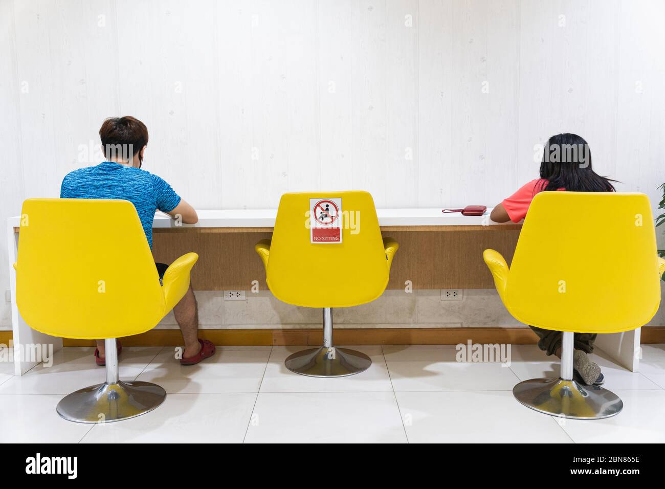 Yong woman and man sitting on the public chair has restricted no ...