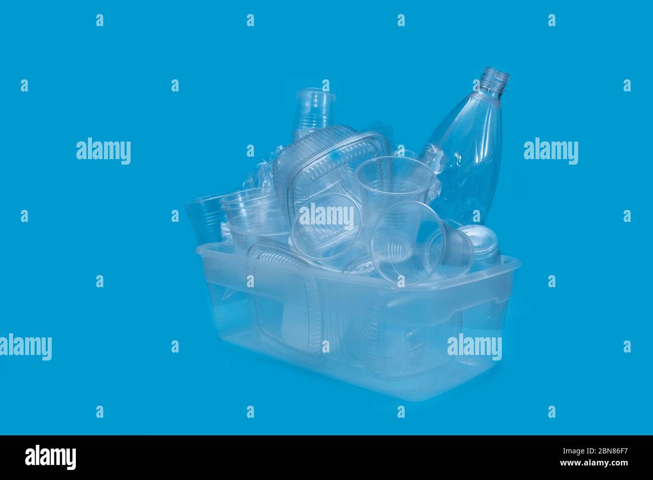 A lot of different plastic crockery and containers on blue background ...