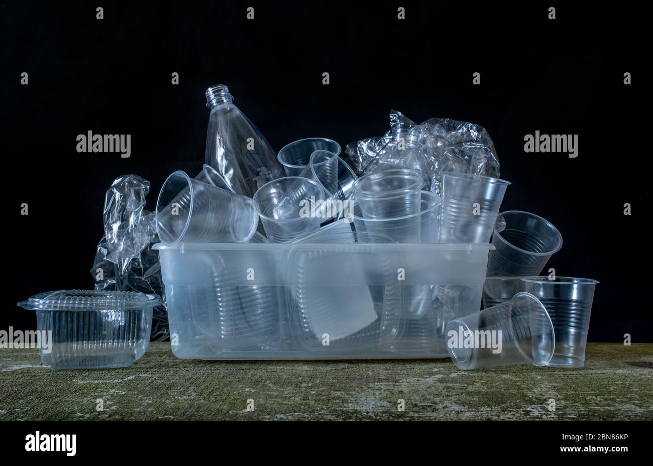 A lot of different plastic crockery and containers on black background ...