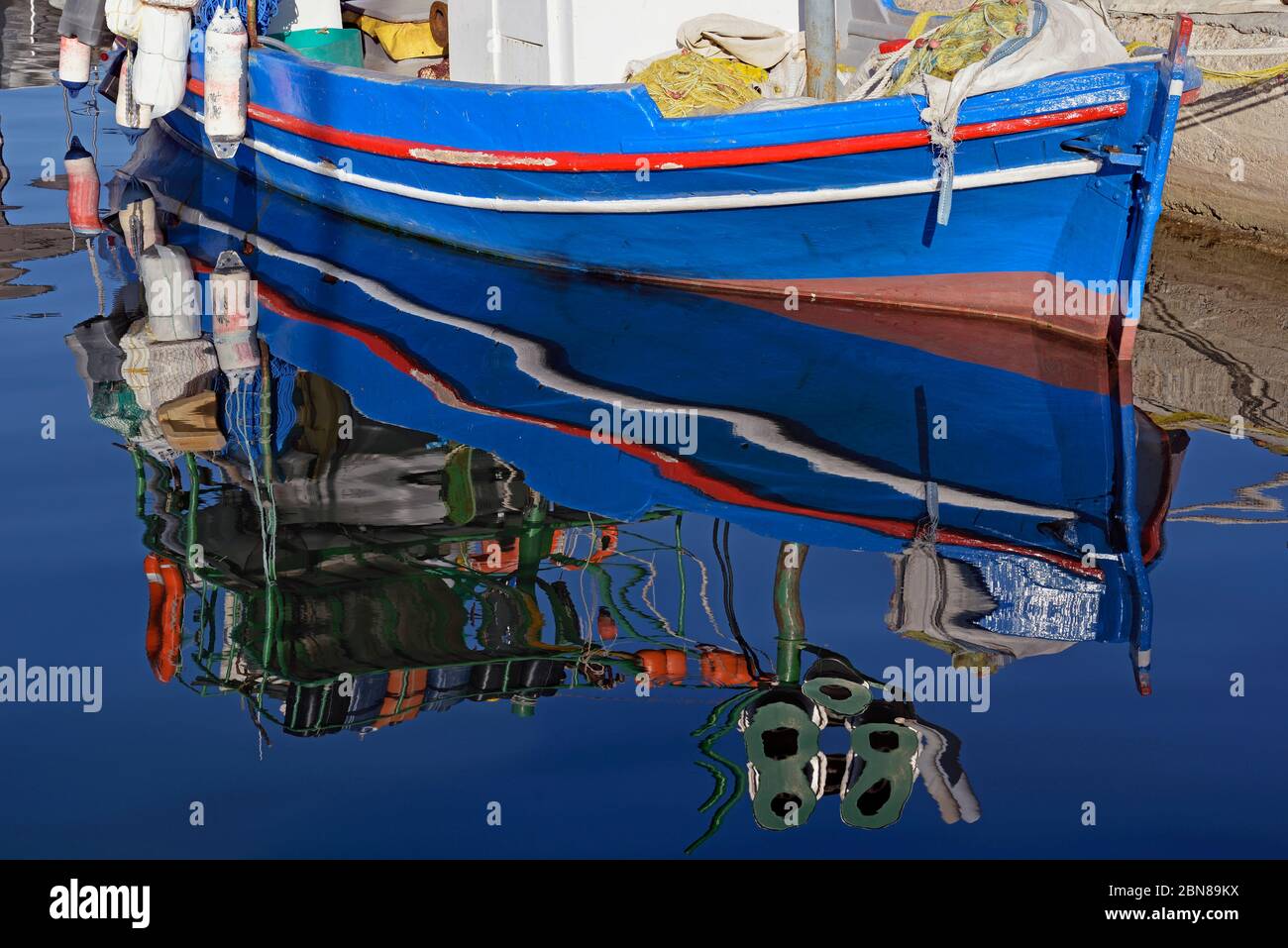 A fishing boat and its reflection Stock Photo - Alamy