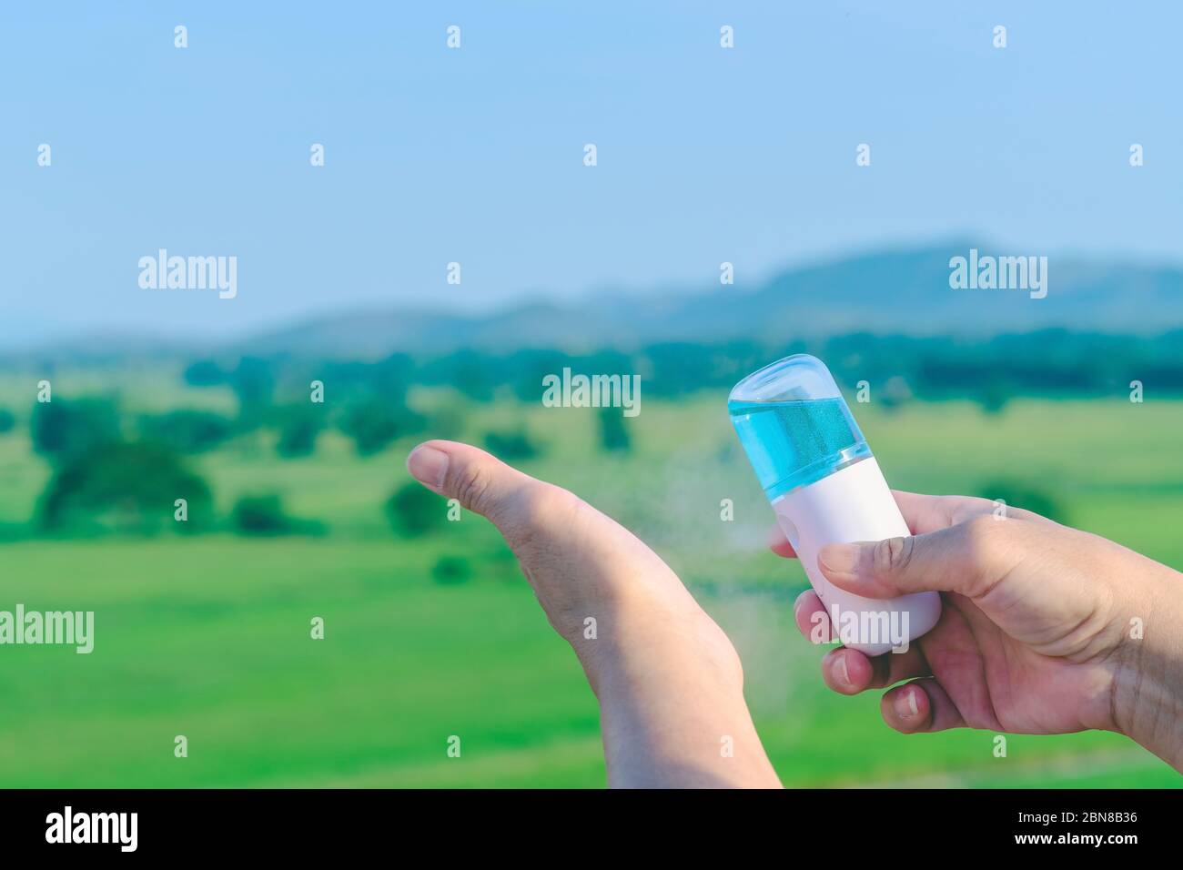 Woman using alcohol nano mist sprayer antiseptic cleaning on her hands ...