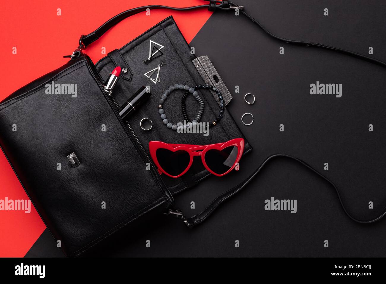 Flat lay top view open bag with accessories on double red and black ...