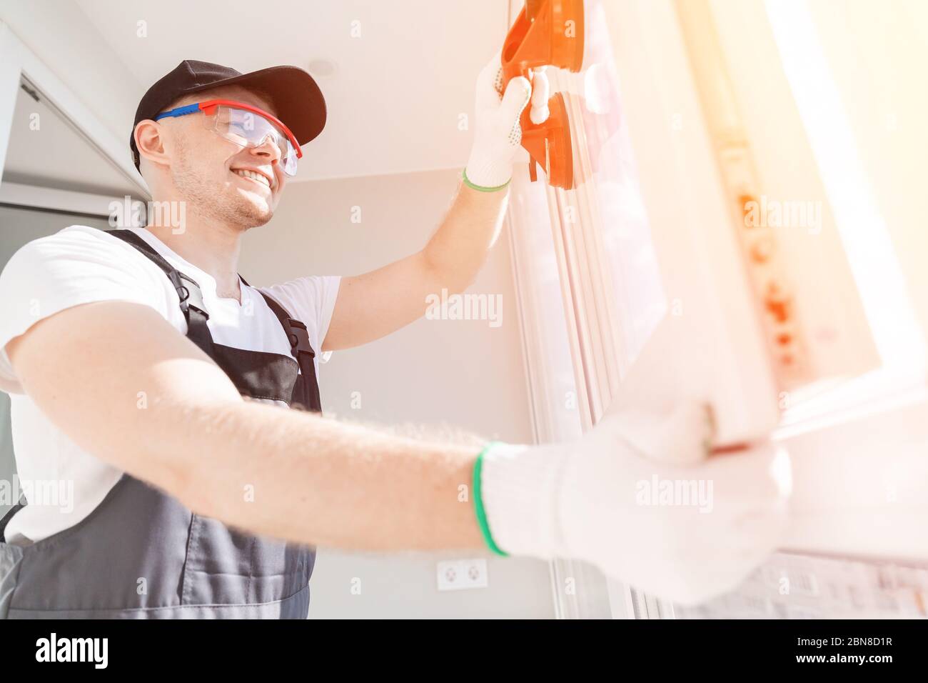 Worker man installs plastic windows and doors with double-glazed white ...