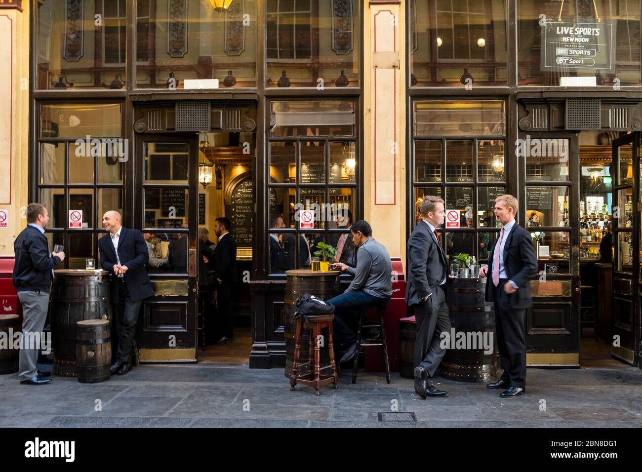 Male office workers drink inside and outside a British pub in ...