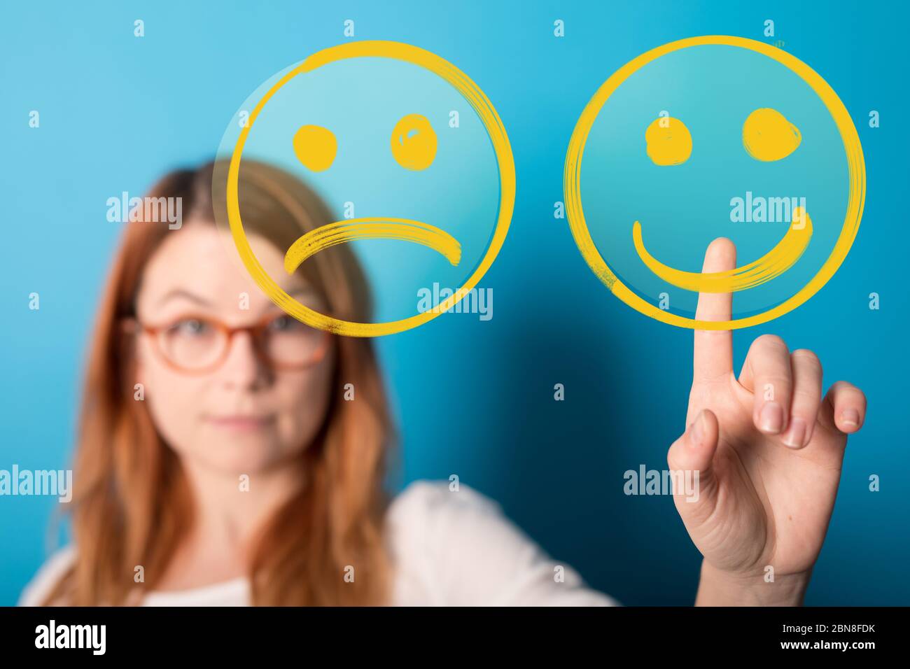 A Hand is selecting a happy mood smiley. In front of an empty room ...