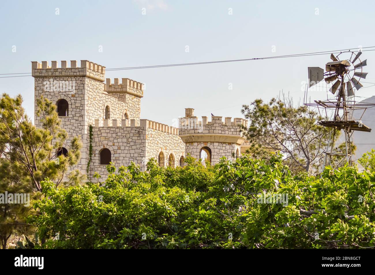 Modern villa in the shape of a small fortress with a wind turbine on ...