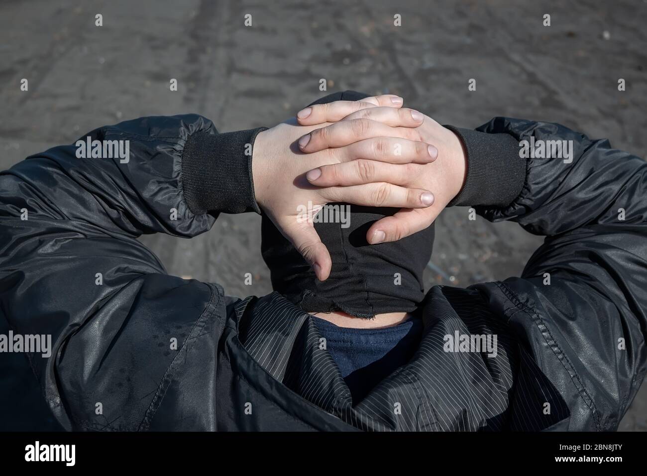 the hands of the detained bandit are closed behind the head, which is ...