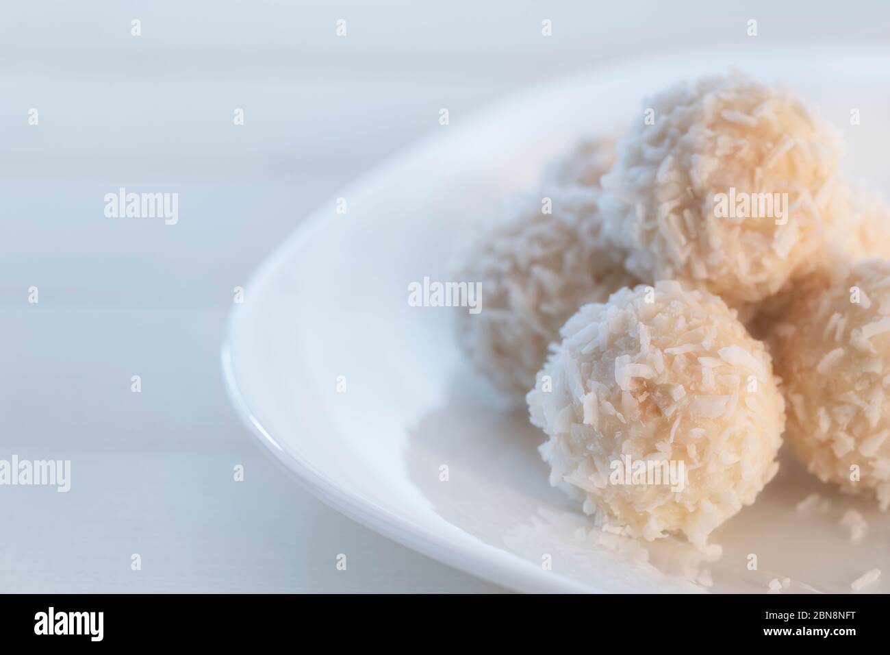 Coconut candy balls in plate covered with chocolate and shredded ...