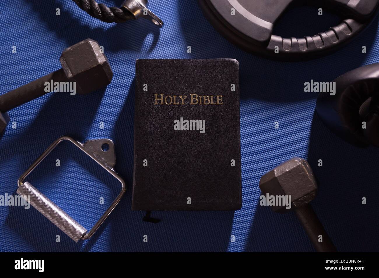 Holy Bible surrounded by dumbbells weights and other exercise equipment ...