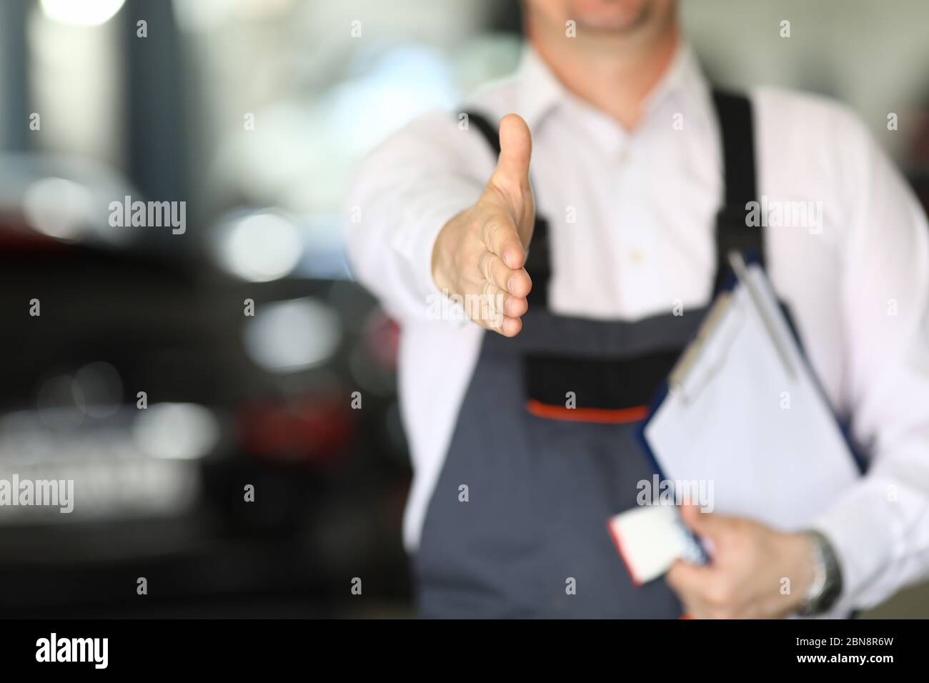 Car dealership male employee holds out his hand Stock Photo - Alamy