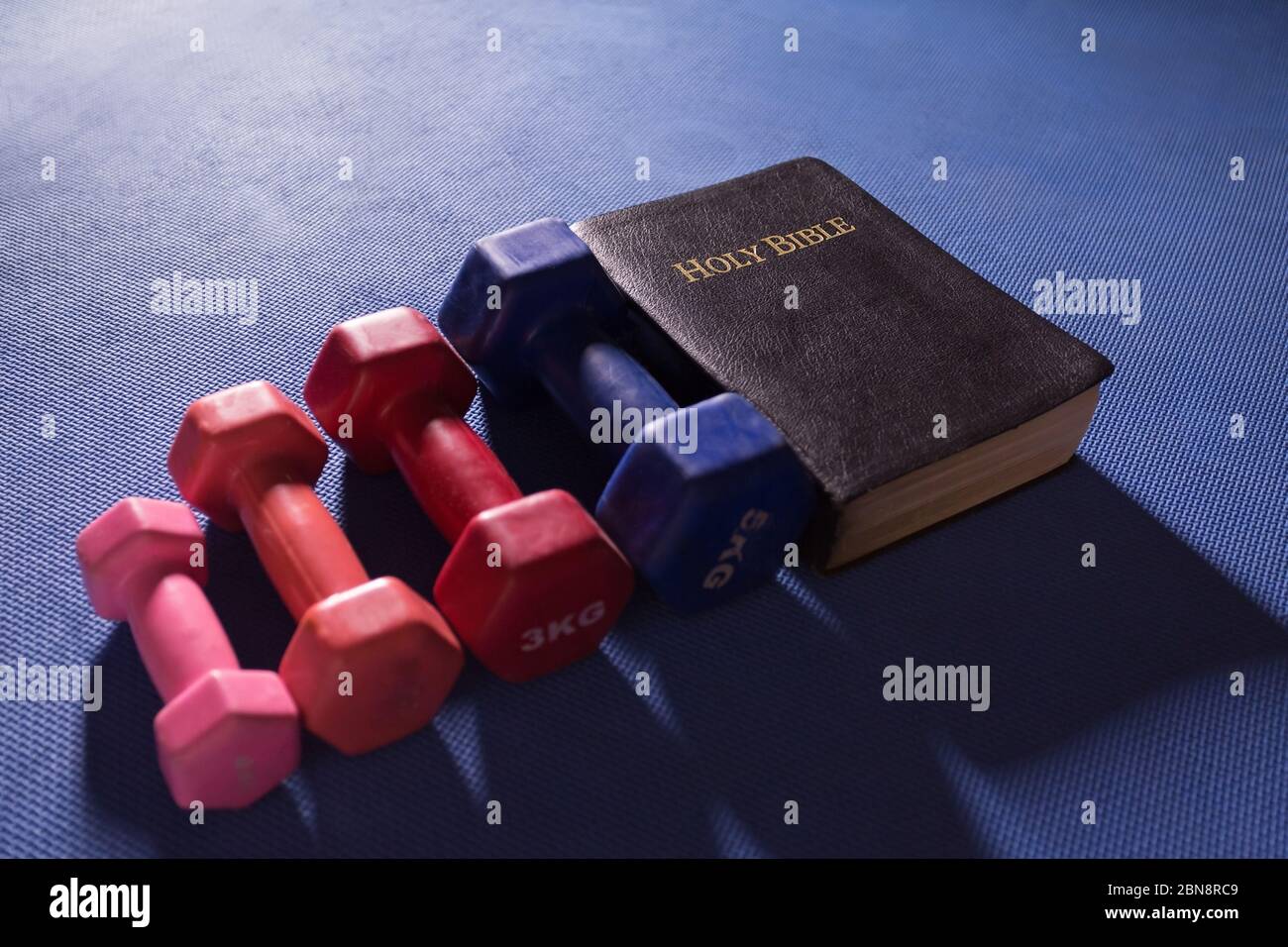 Dumbbells on a blue gym workout mat next to the Holy Scriptures Stock ...