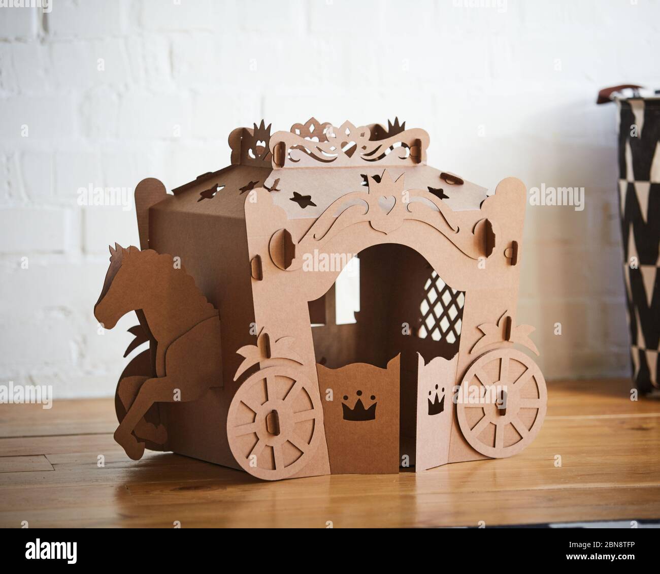 A horse and a carriage made of brown cardboard,where the horse is ...