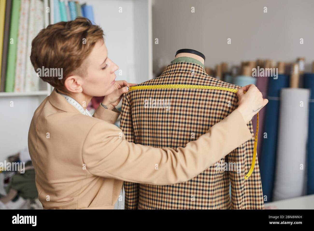 Tailor measuring shoulder length on the jacket with tape measure before ...
