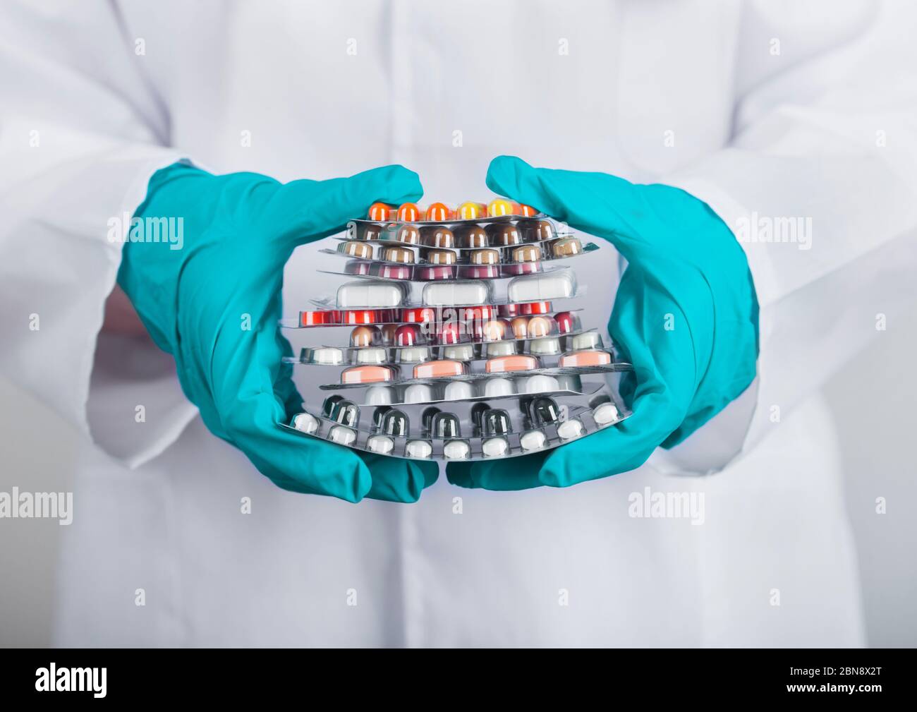 Hands in green latex gloves holding stack of different pills ...