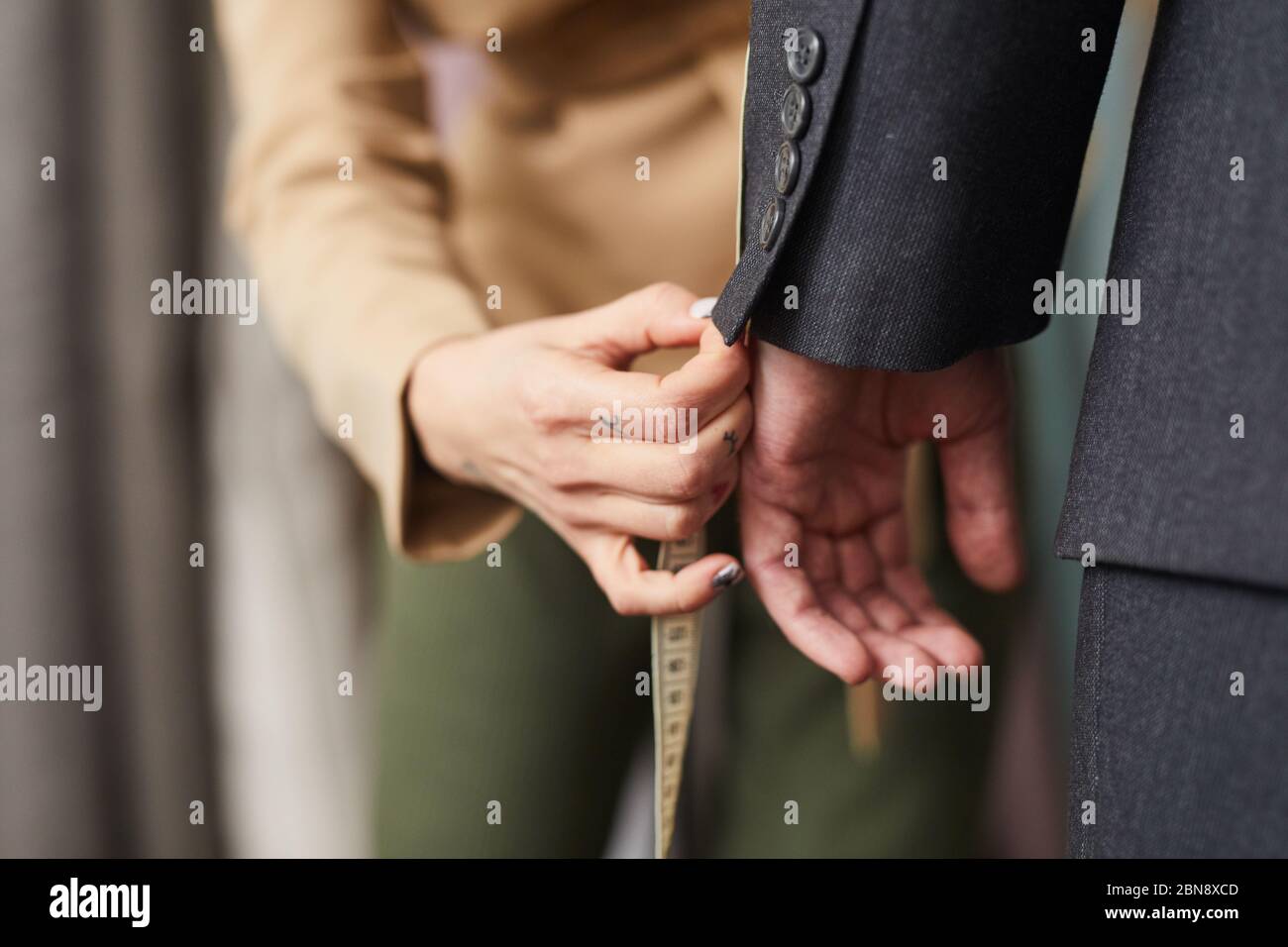 Close-up of tailor measuring the sleeve of suit with tape measure Stock ...