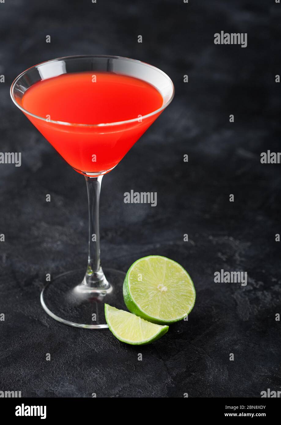 Cosmopolitan cocktail in classic crystal glass with limes on black ...