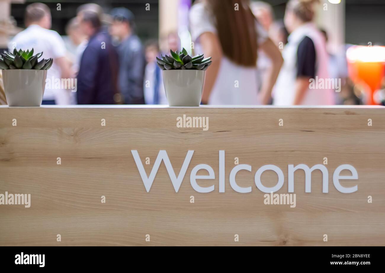 light wooden reception stand with a white inscription welcome. on a ...