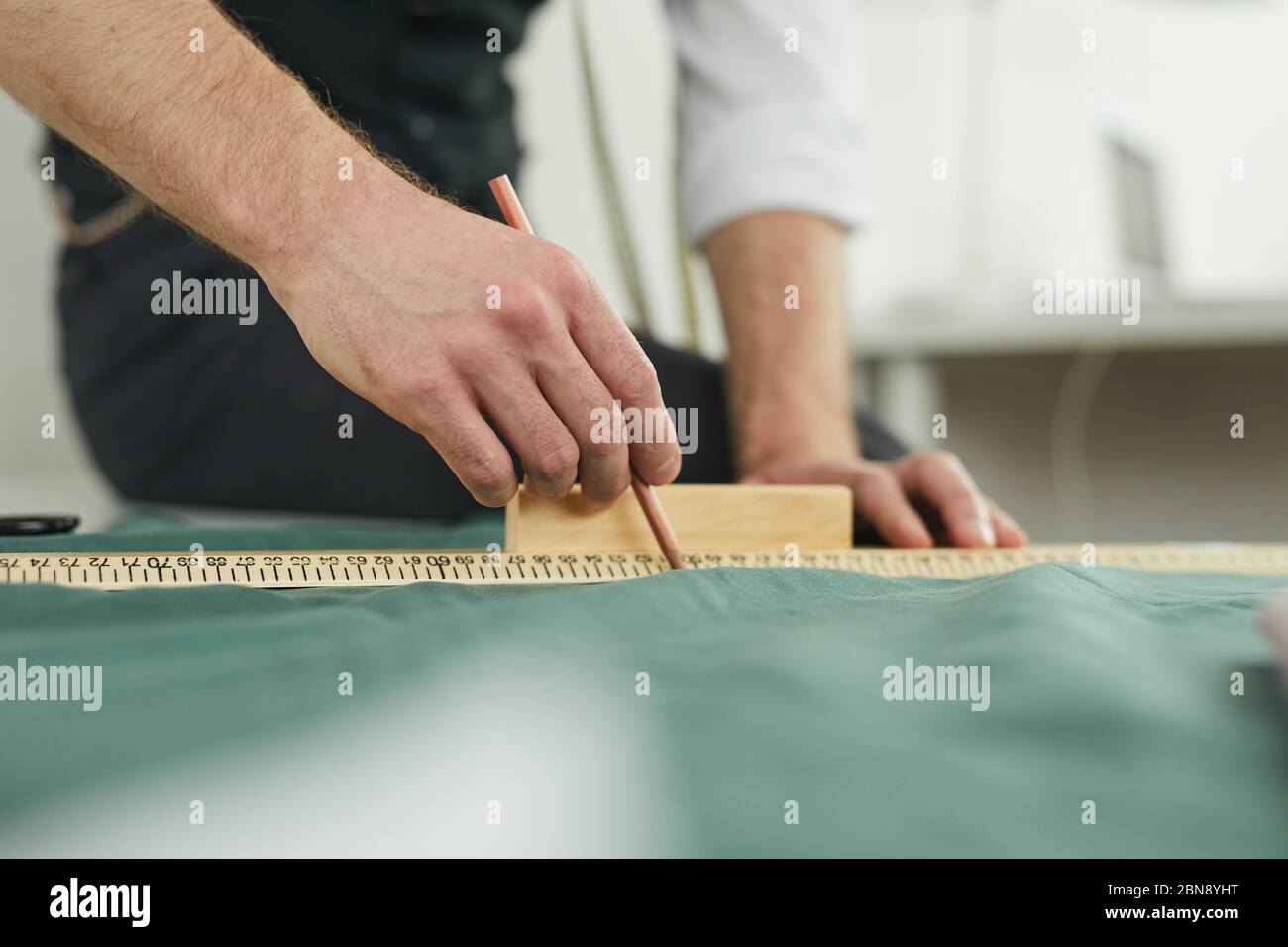 Close-up of designer using ruler and drawing on textile while sewing ...