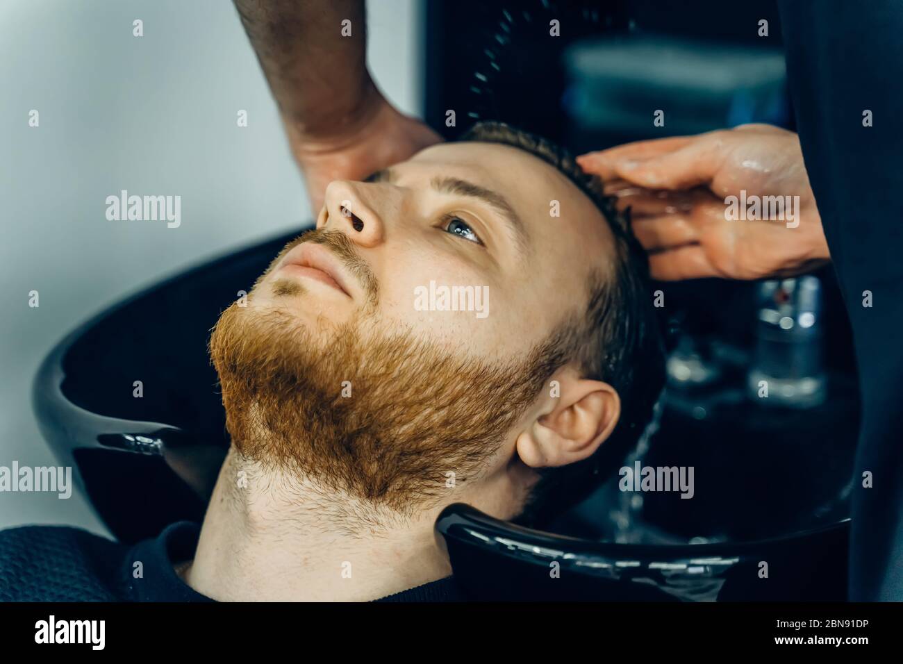 Attractive male is getting a modern haircut in barber shop. Top view of ...