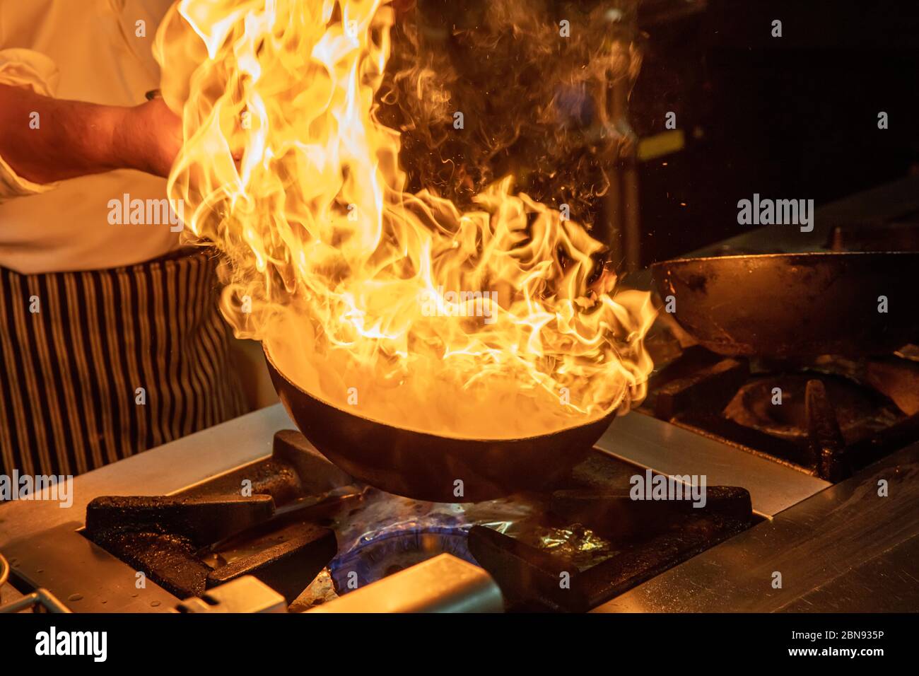 Chef Cooking With Fire In Frying Pan. Professional chef in a commercial ...