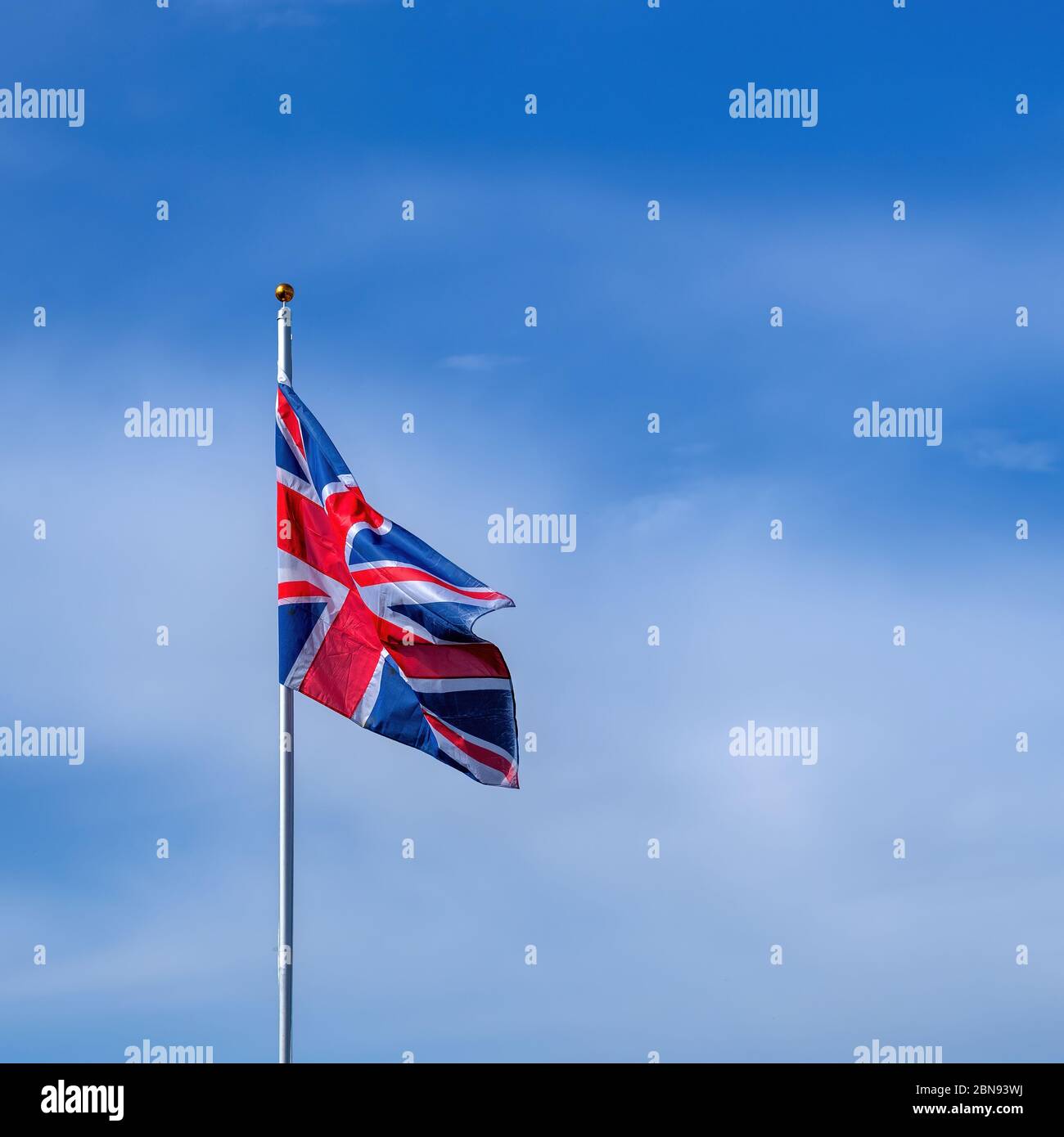 Great Britain Union Jack flag flying on a flagpole in breeze with blue sky and copy space Stock ...