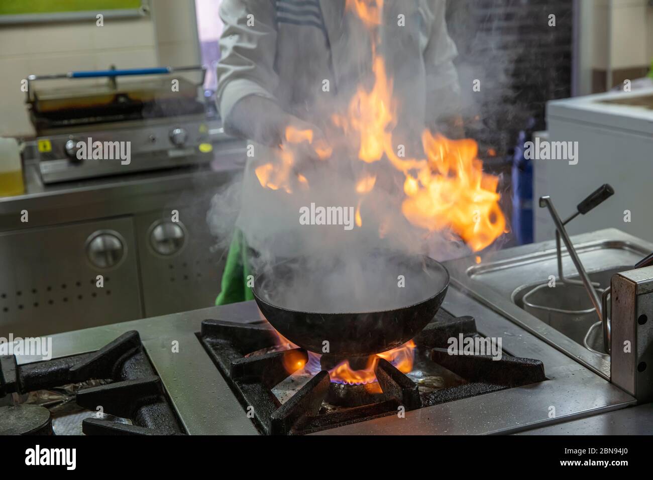 Chef Cooking With Fire In Frying Pan. Professional chef in a commercial ...
