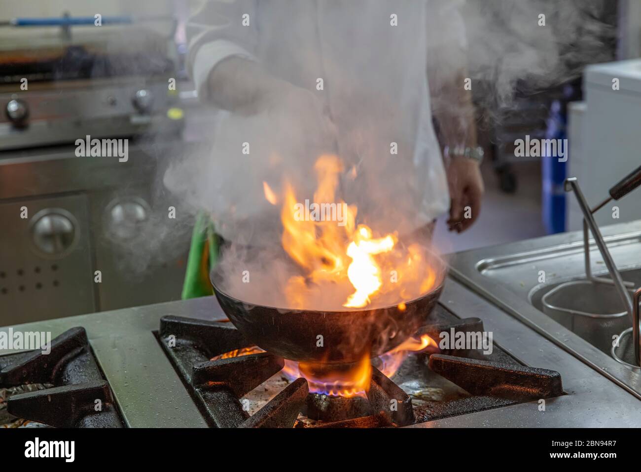 Chef Cooking With Fire In Frying Pan. Professional chef in a commercial ...