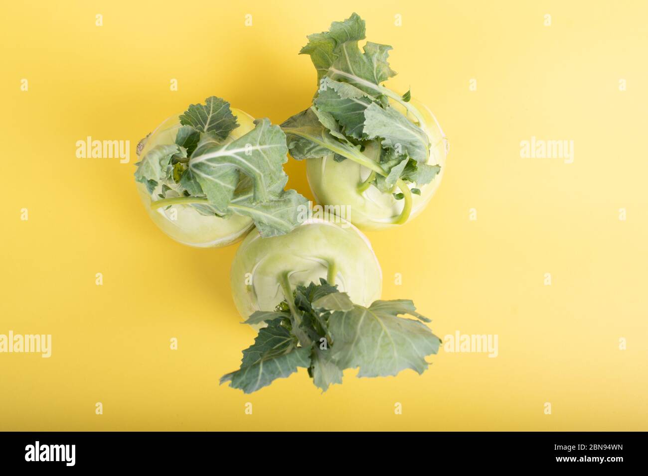Three pieces of kohlrabi vegetable isolated on yellow simple background ...