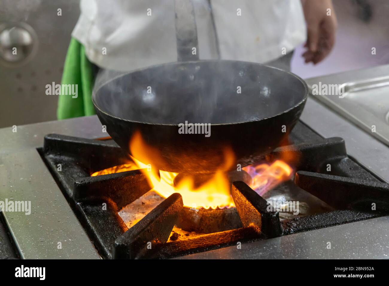 Chef Cooking With Fire In Frying Pan. Professional chef in a commercial ...