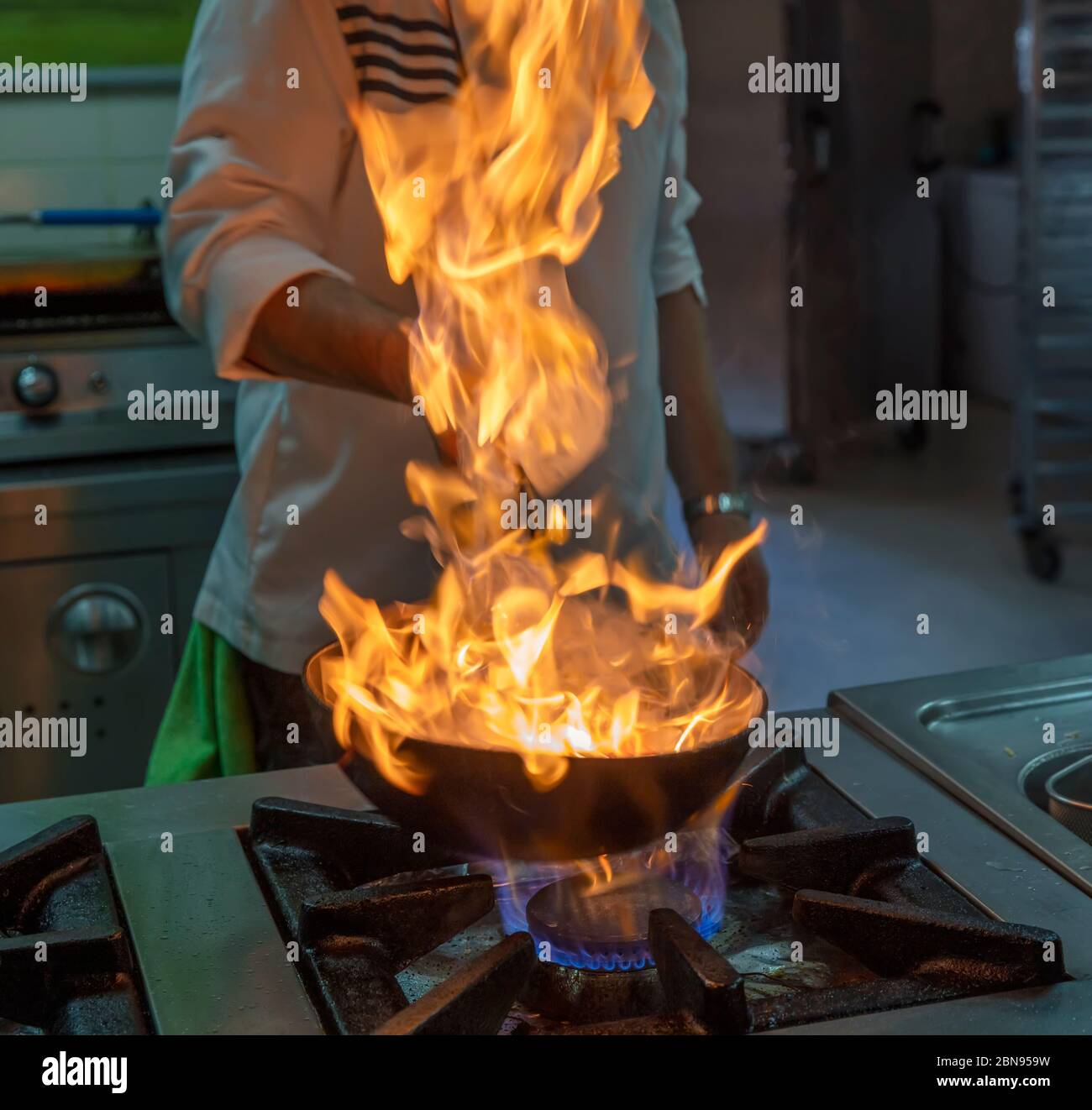 Chef Cooking With Fire In Frying Pan. Professional chef in a commercial ...