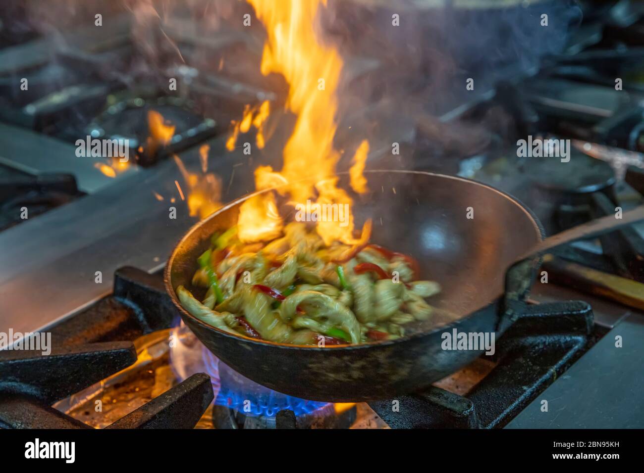 Chef Cooking With Fire In Frying Pan. Professional chef in a commercial ...