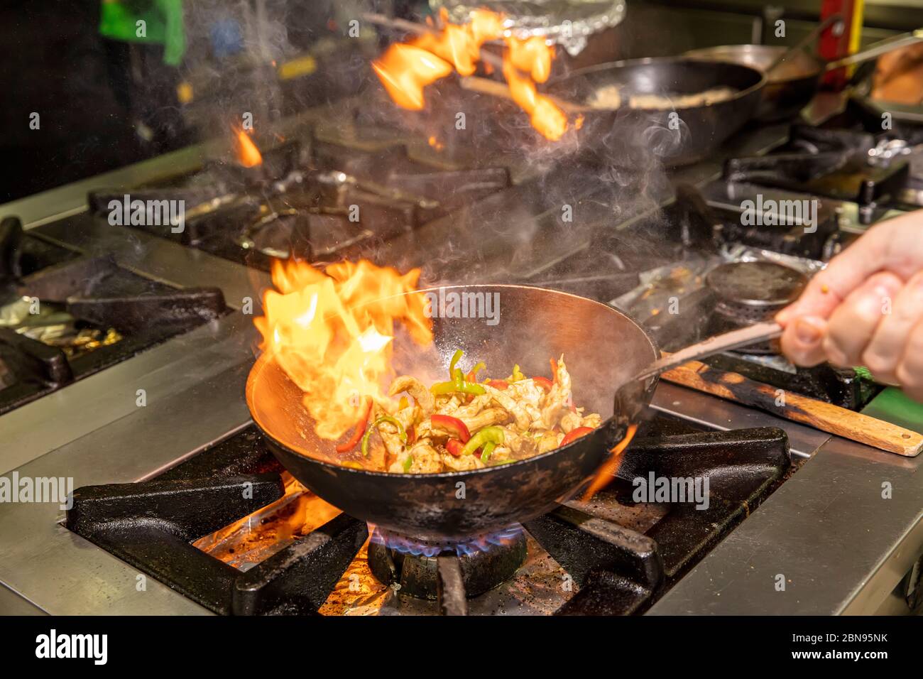 Chef Cooking With Fire In Frying Pan. Professional chef in a commercial ...