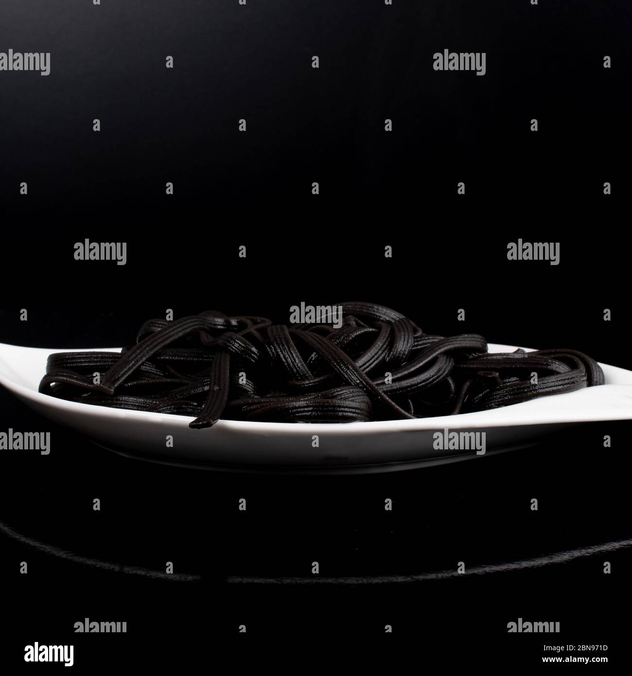 Black tagliatelle (pasta made with cuttlefish ink) on white elegant and ...