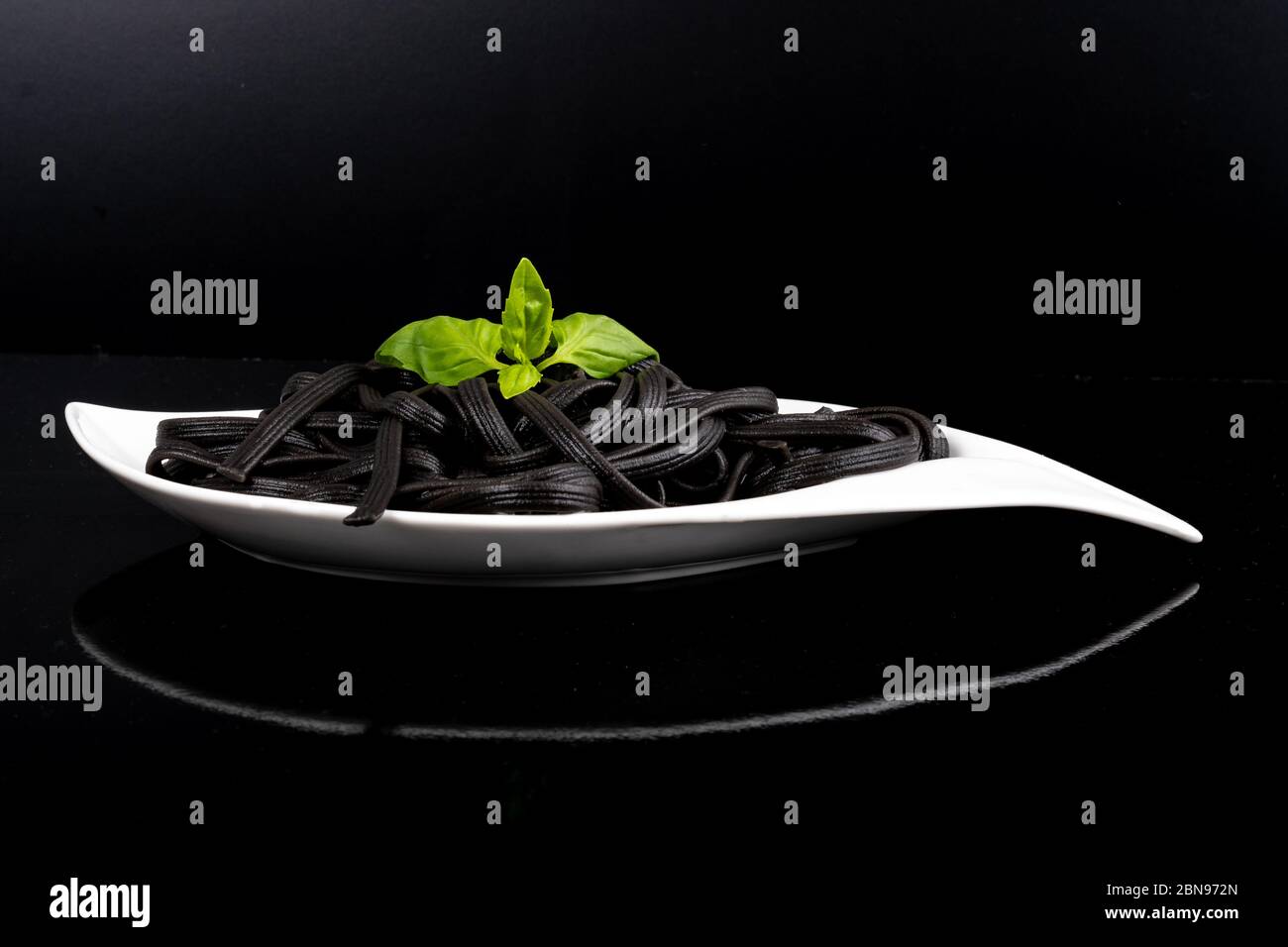 Black tagliatelle (pasta made with cuttlefish ink) on white elegant and ...