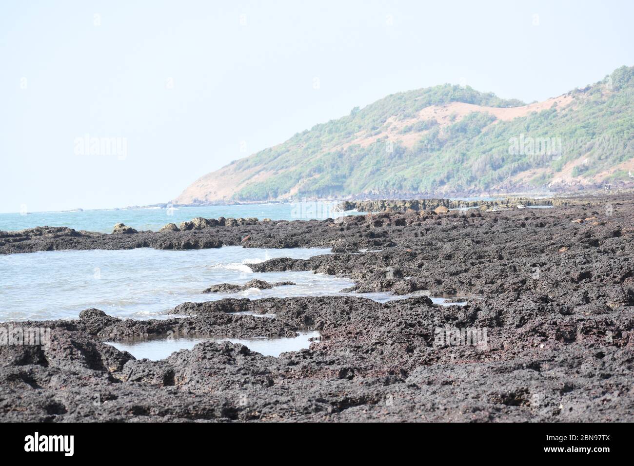 Black rocks in the seashore and mountain in the background..A view from ...