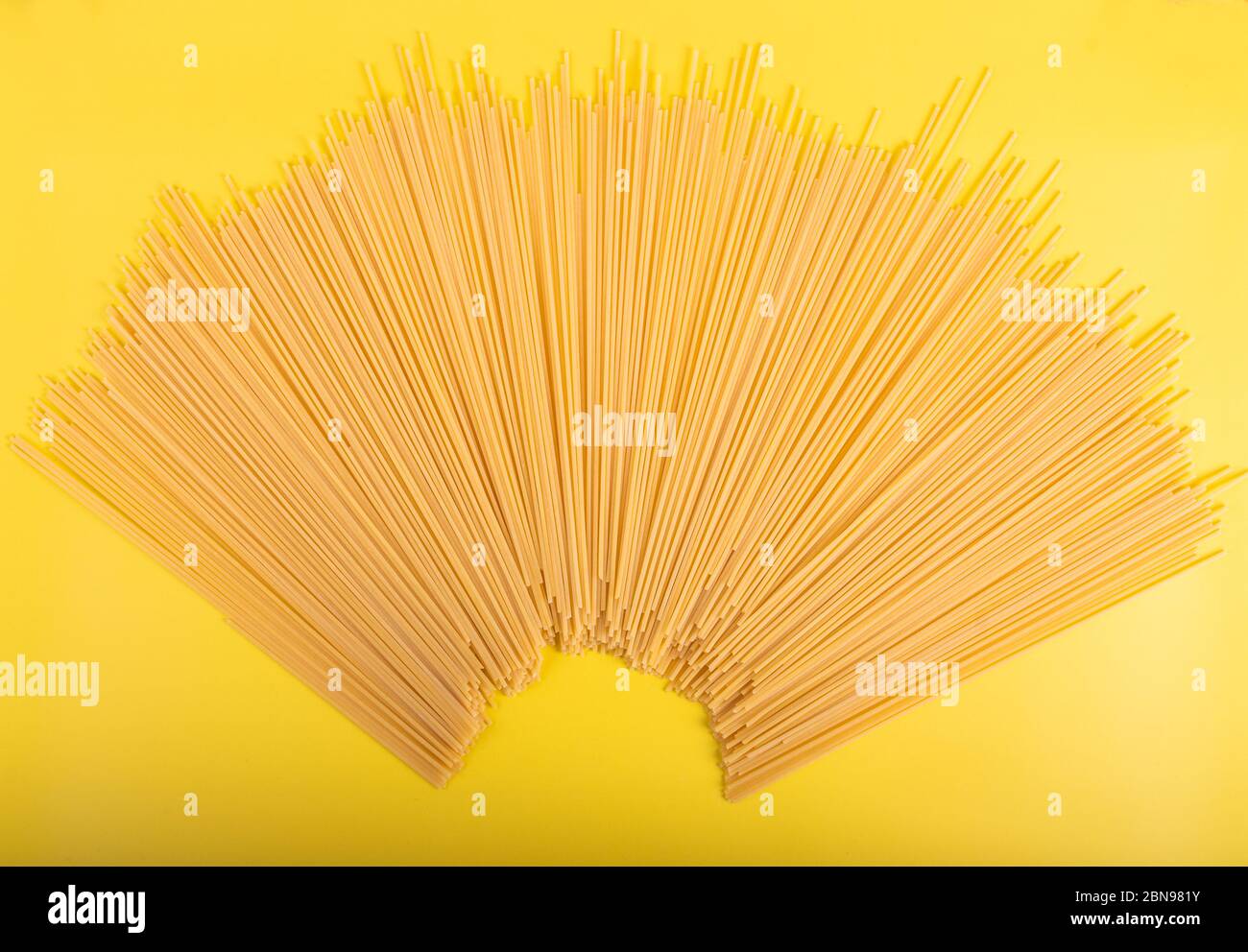 Uncooked yellow long spaghetti on a rustic background. Yellow italian ...