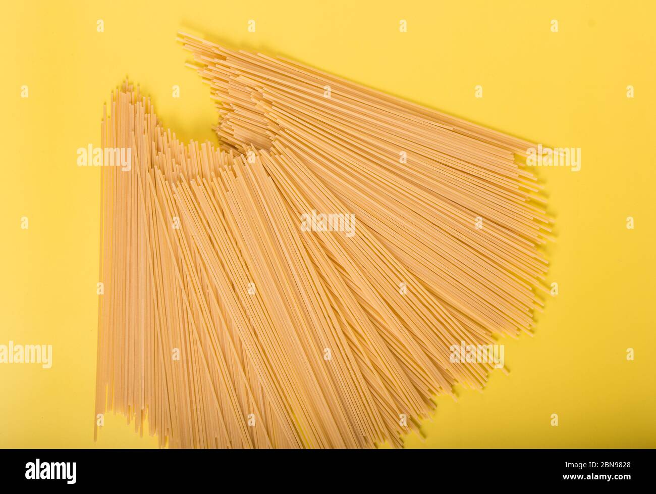 Uncooked yellow long spaghetti on a rustic background. Yellow italian ...