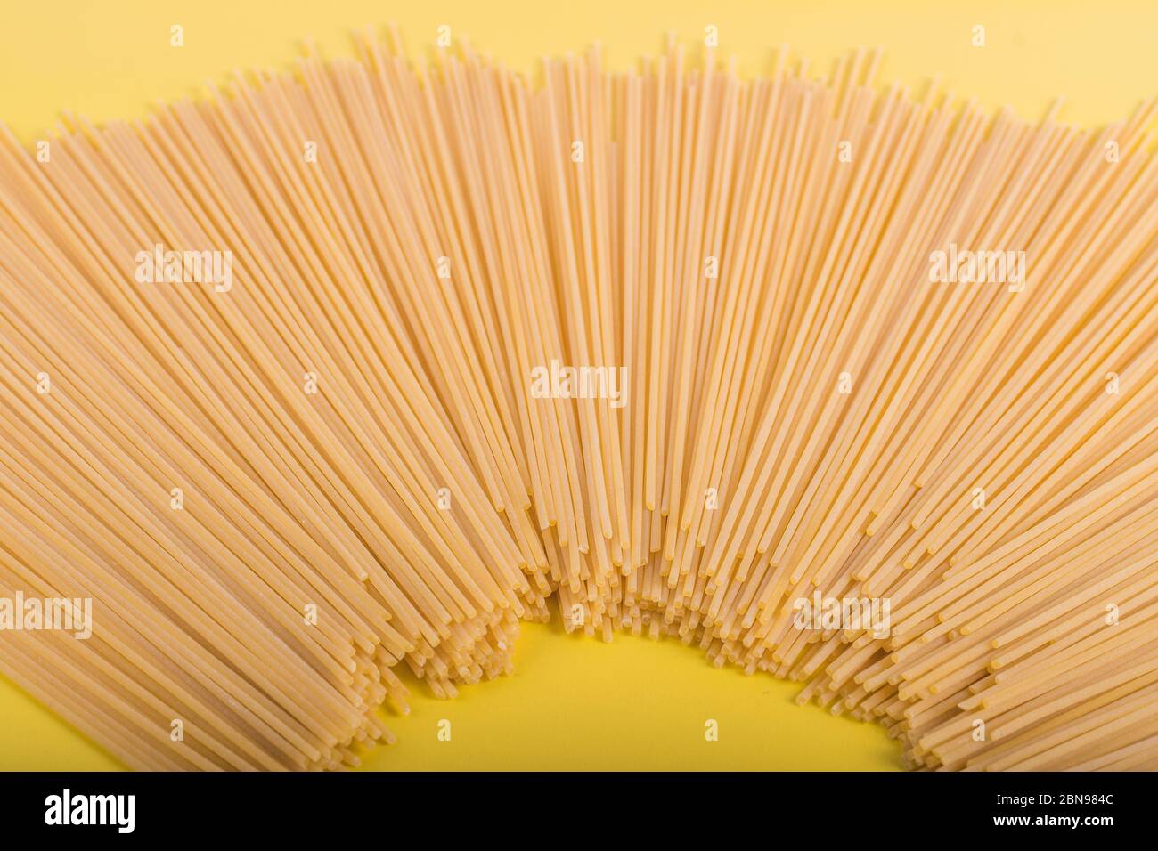 Uncooked yellow long spaghetti on a rustic background. Yellow italian ...