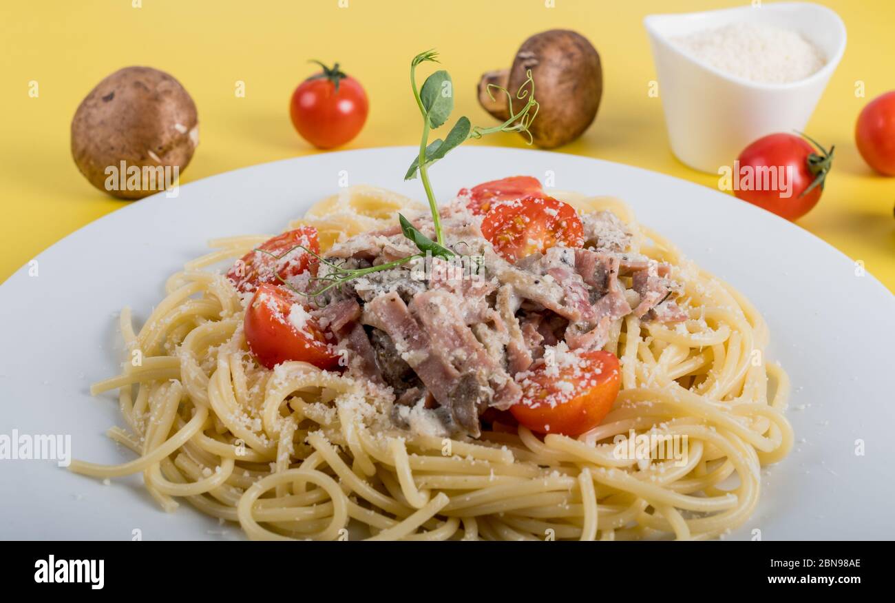 Spaghetti cooked pasta with ingredients on a yellow background ...