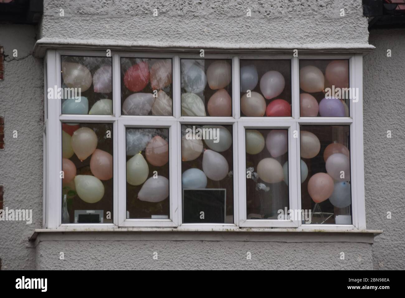 Coloured balloons in window Stock Photo - Alamy