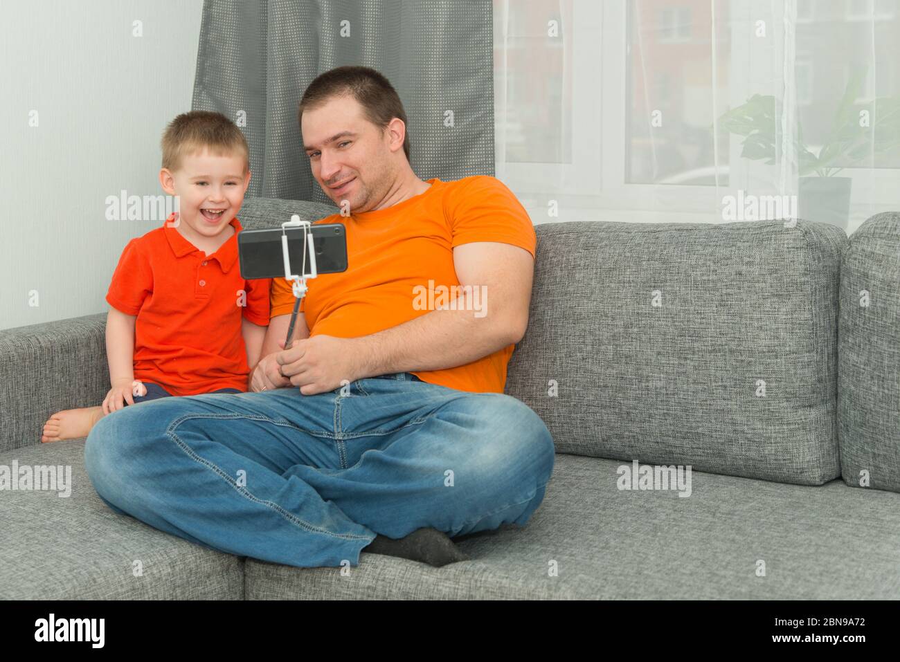Boy and man looking in the smartphone during online call and smiling ...