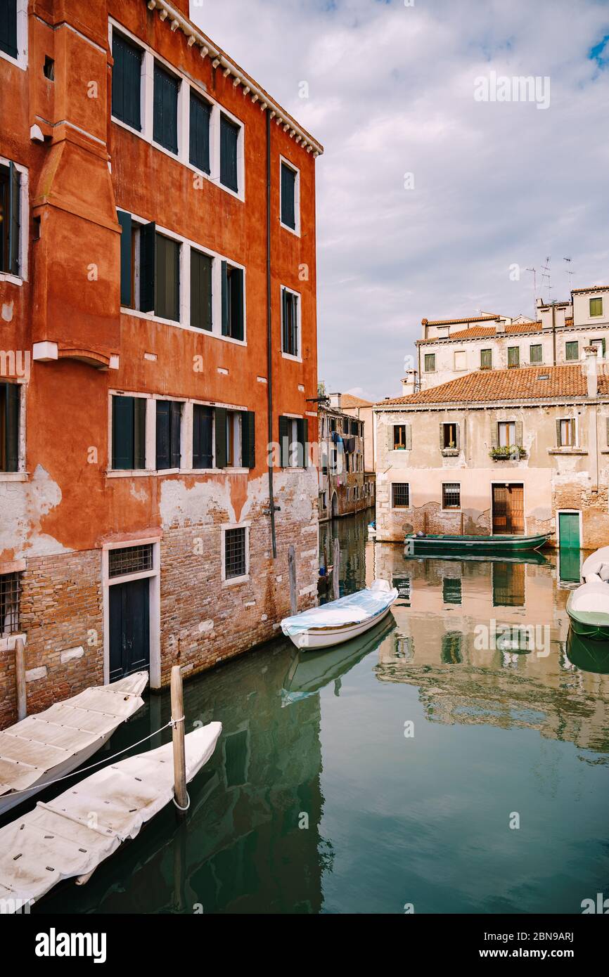 Boats moored at the walls of a building in a canal in Venice, Italy ...