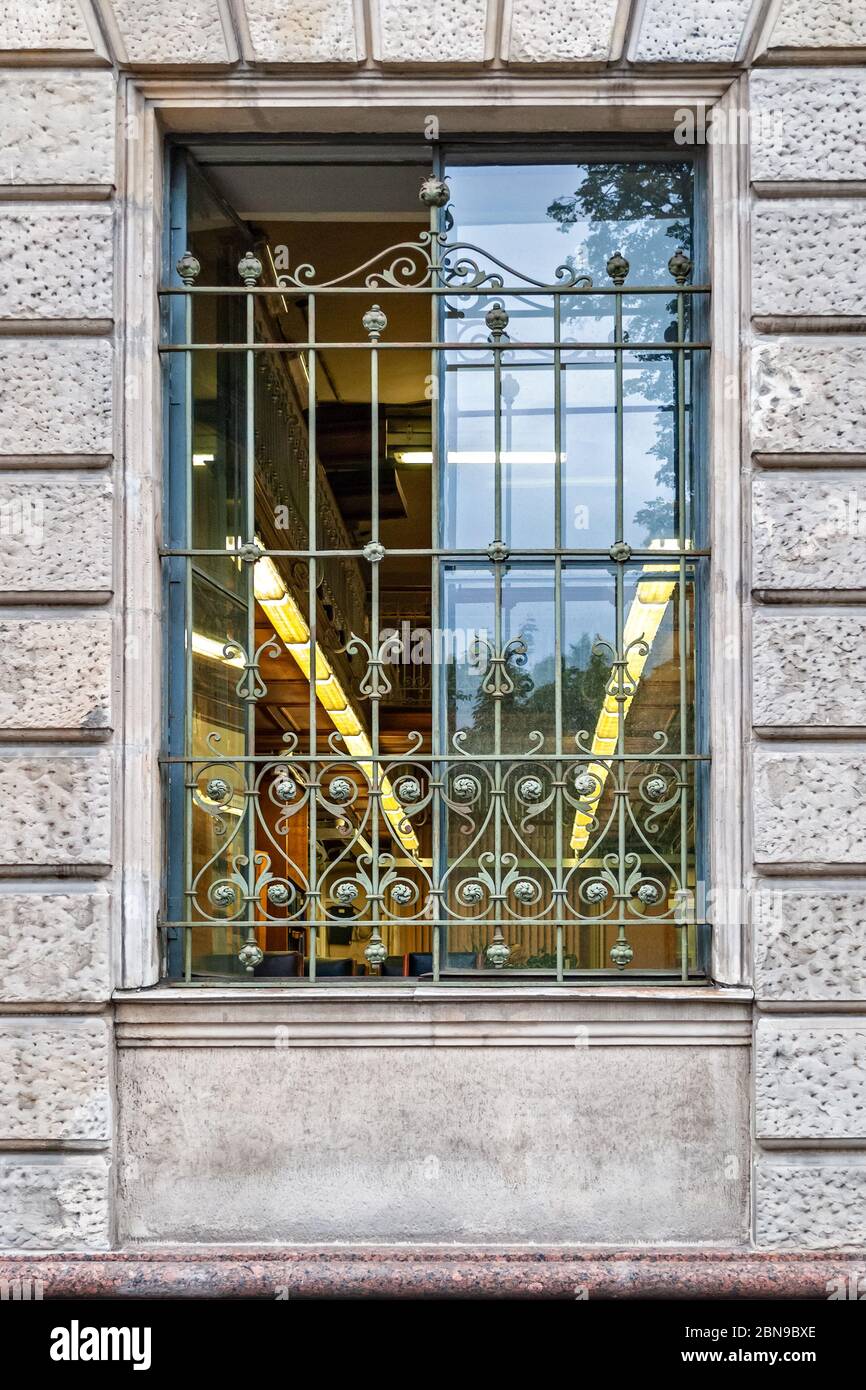 Rectangular window with metal bars on a gray wall background. From a ...