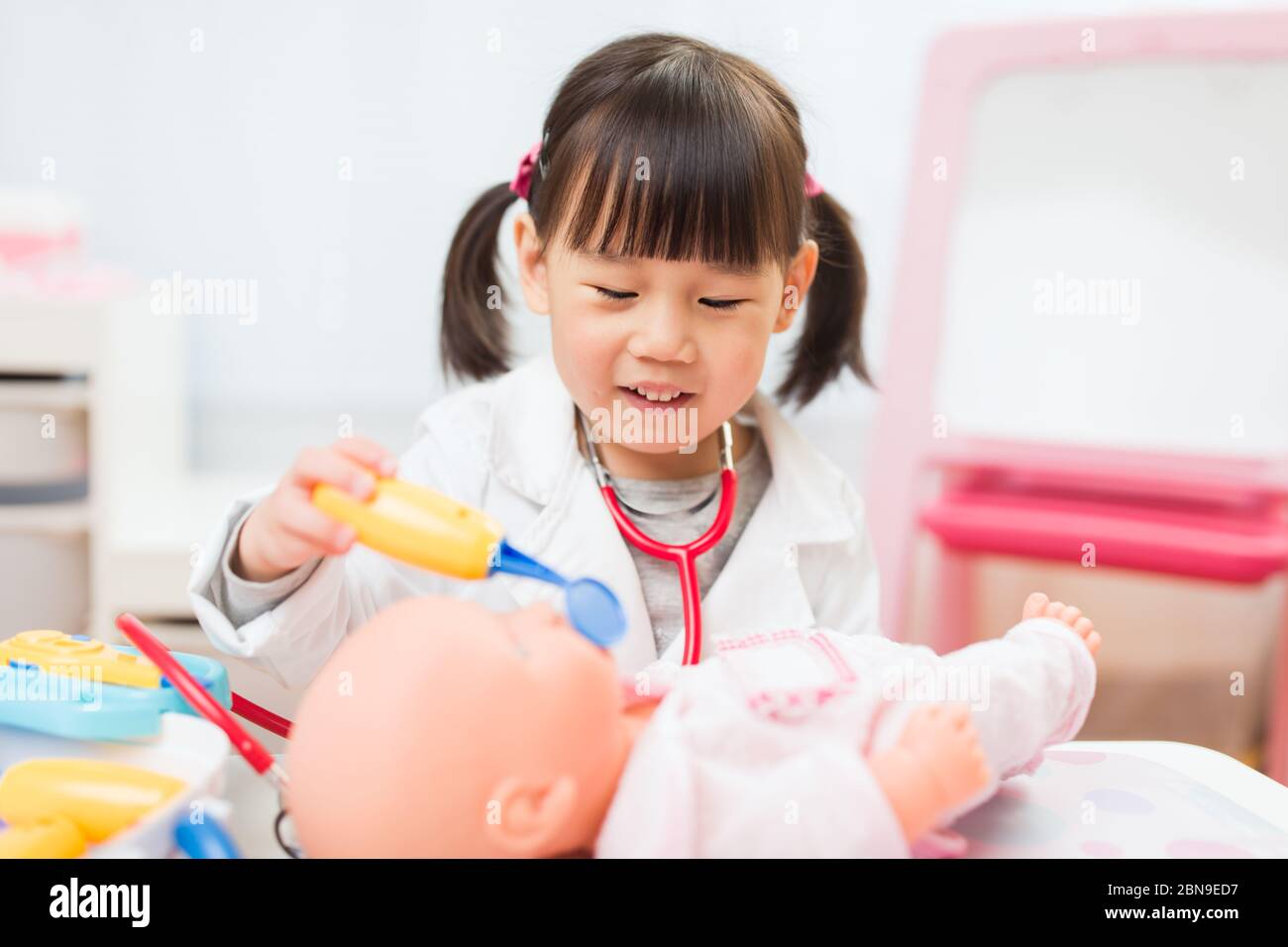 toddler girl pretend play doctor role at home against white background ...